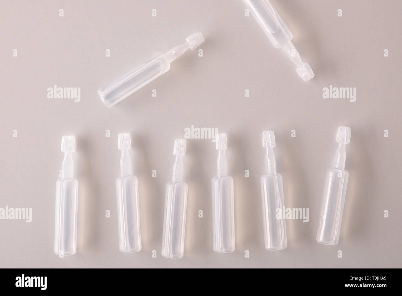 Several pipettes of eye drops spread on white table. Horizontal ...