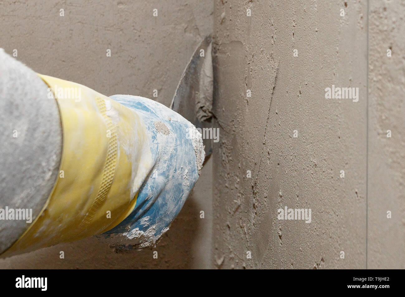 Hand with a spatula in the process of leveling the raw plaster Stock ...