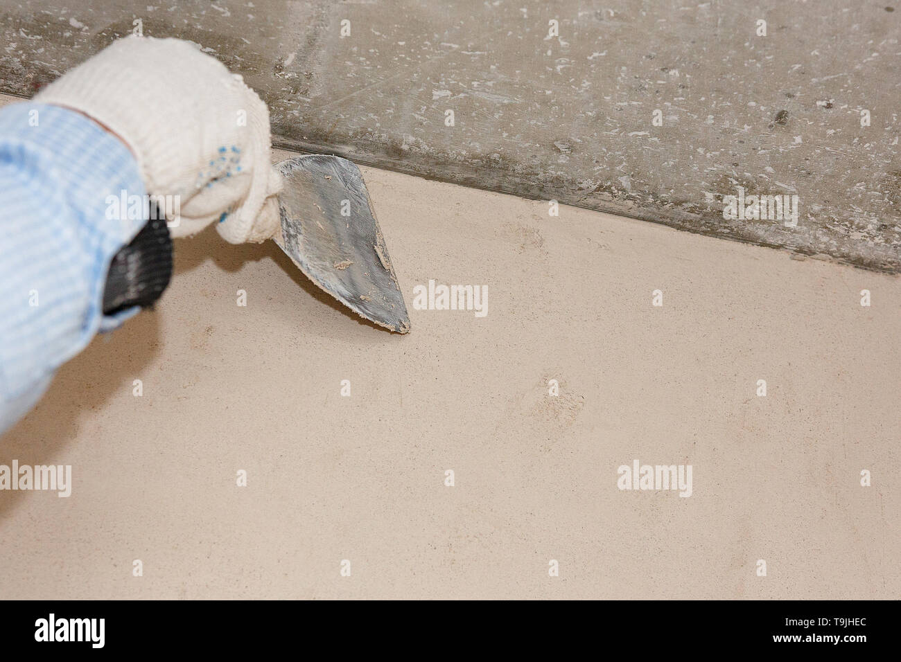 Hand with a spatula in the process of leveling the raw plaster Stock ...