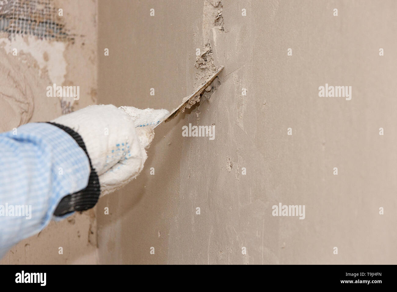 Hand with a spatula in the process of leveling the raw plaster Stock ...