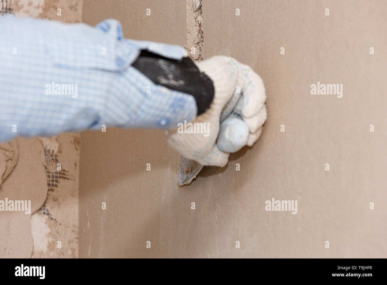 Hand with a spatula in the process of leveling the raw plaster Stock ...