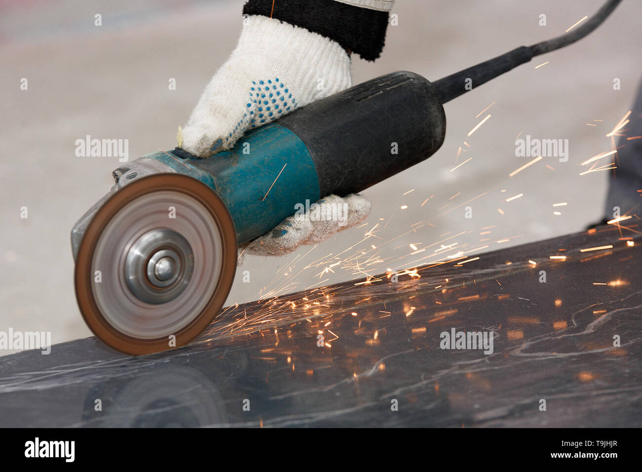 The hand of a worker in a glove cuts the building material with an ...