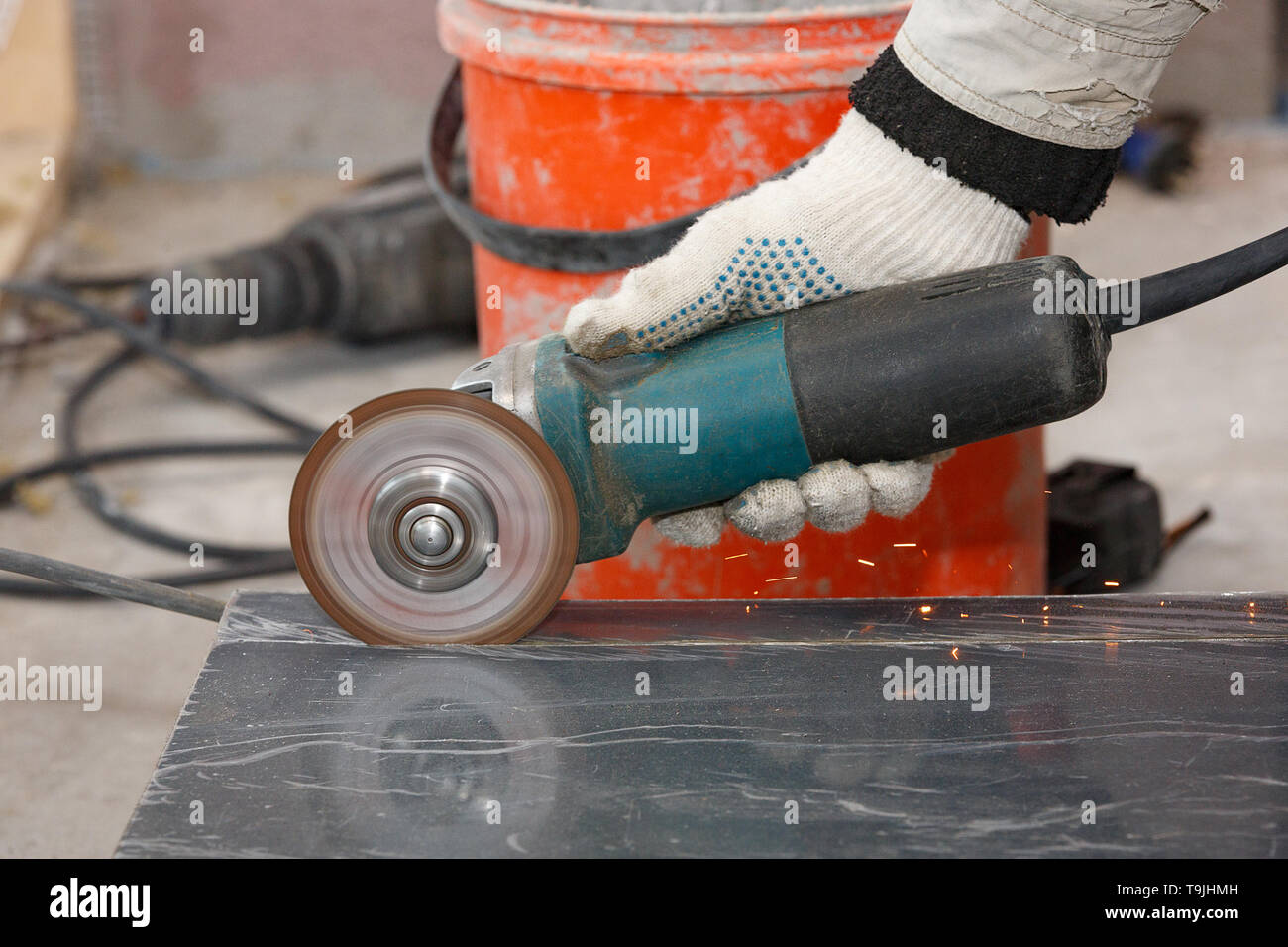 The hand of a worker in a glove cuts the building material with an ...