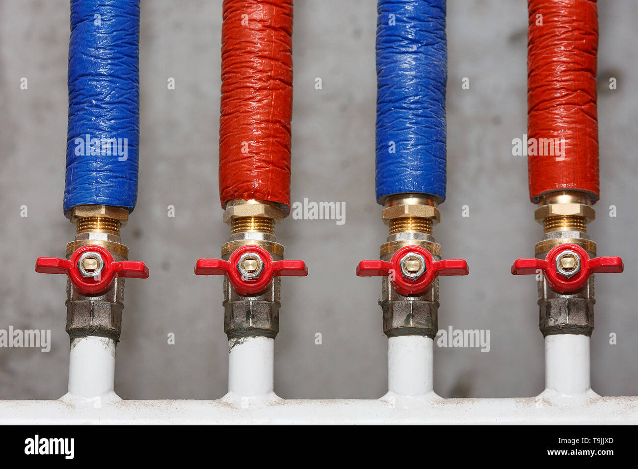 Wiring of hot and cold water supply on the background of a concrete ...
