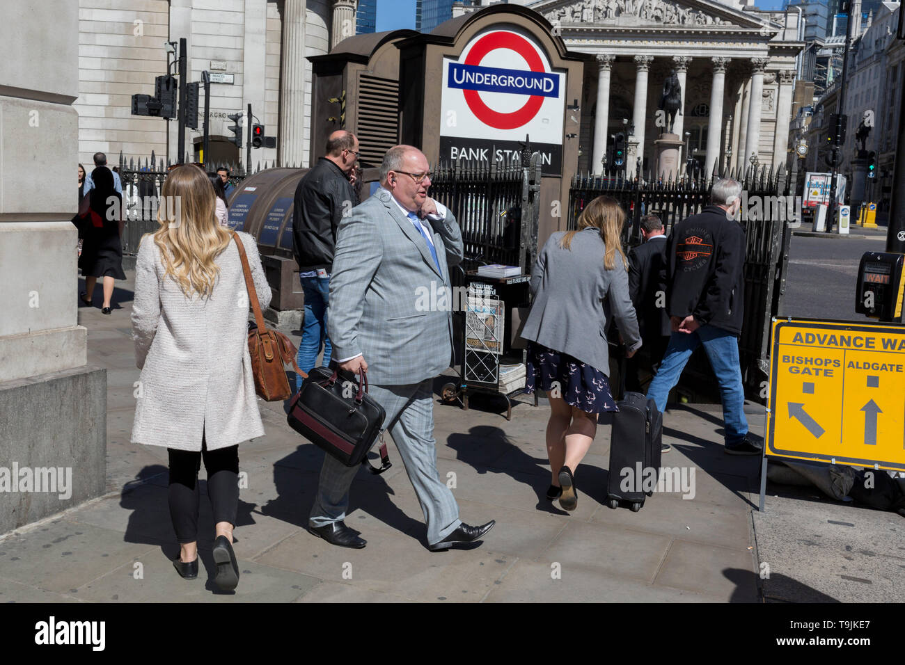 A large middle-aged businessman wearing a silver suit walks past one ...
