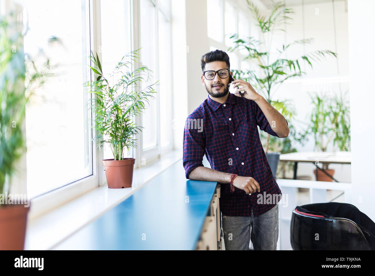 Indian businessman talking on phone in front modern office building ...