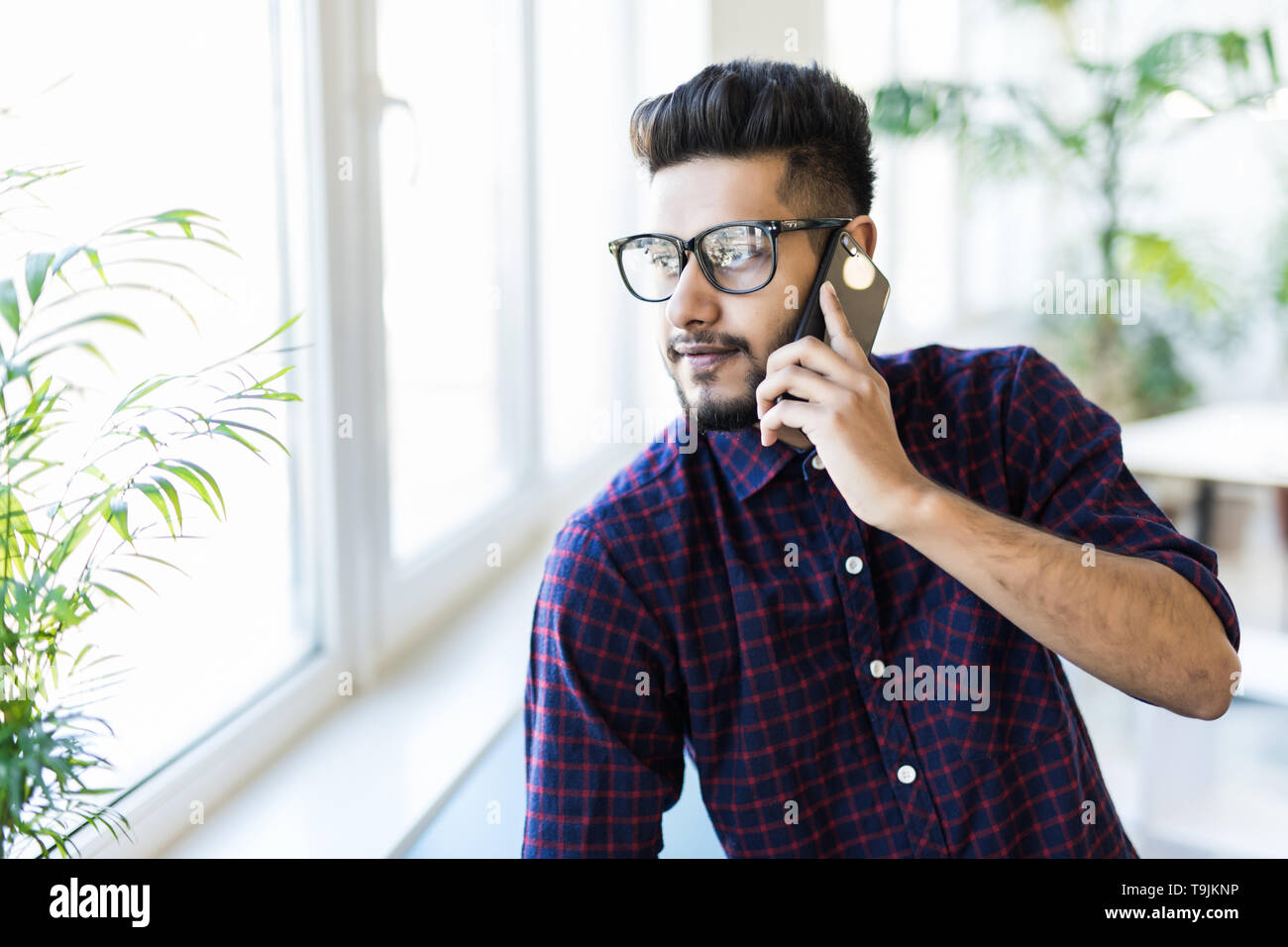 Indian businessman talking on phone in front modern office building ...