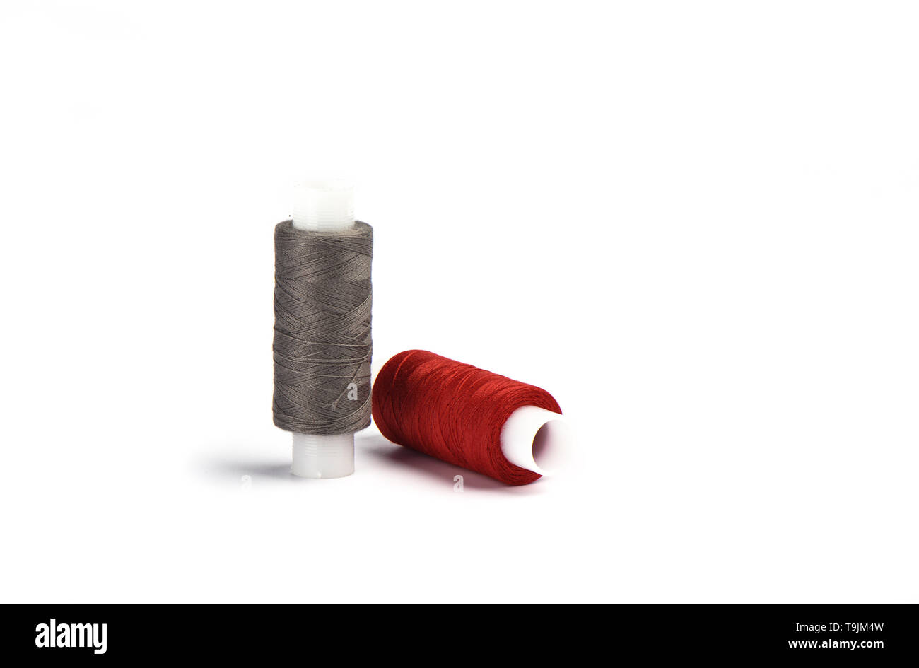 Cotton red and gray threads on the plastic sleeve for the sewing ...