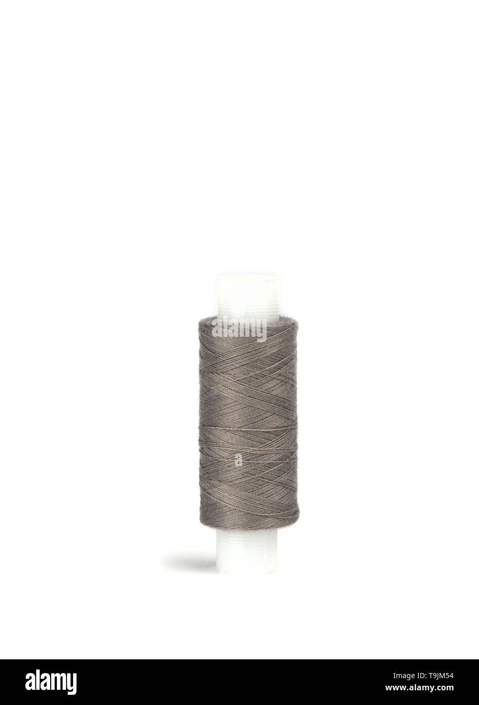Cotton gray threads on the plastic sleeve for the sewing machine ...