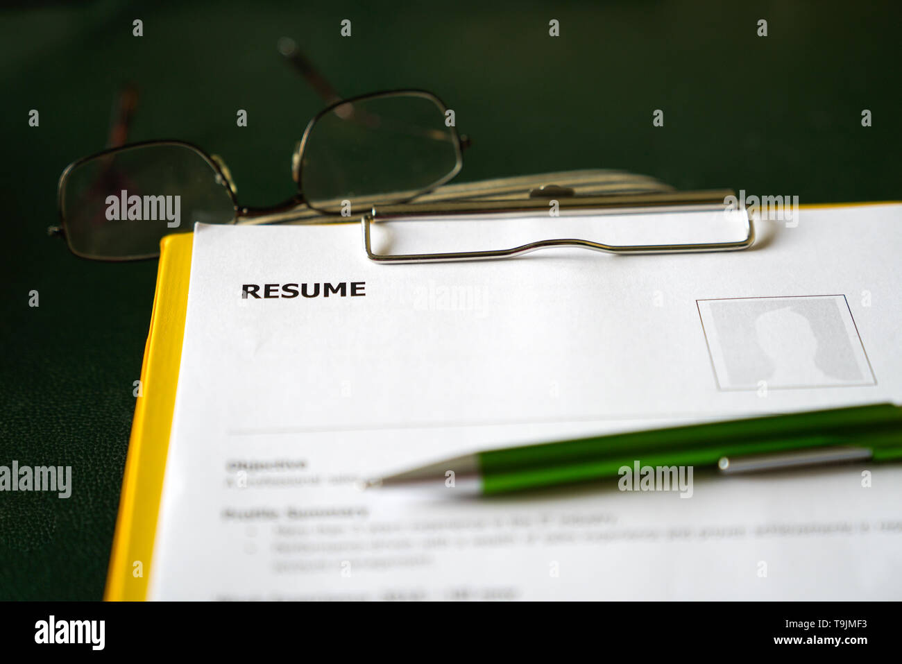 Resume on a clipboard with office table background. A hiring or ...