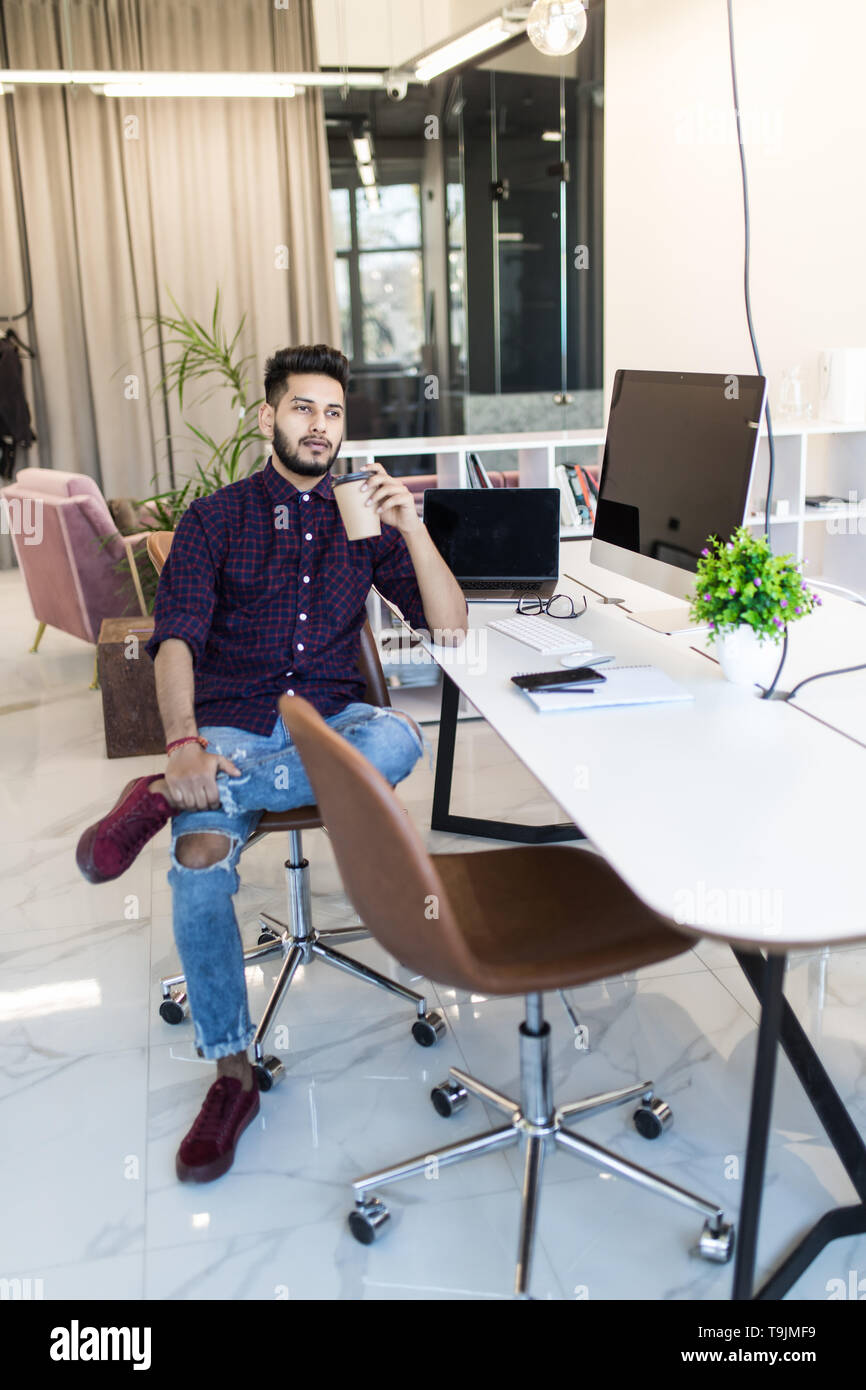 Indian manager with a coffee cup looking at laptop screen Stock Photo ...