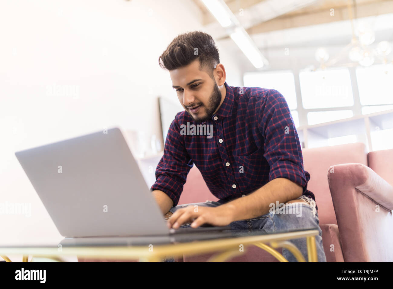Casual young man using laptop with happy on sofa in modern office ...