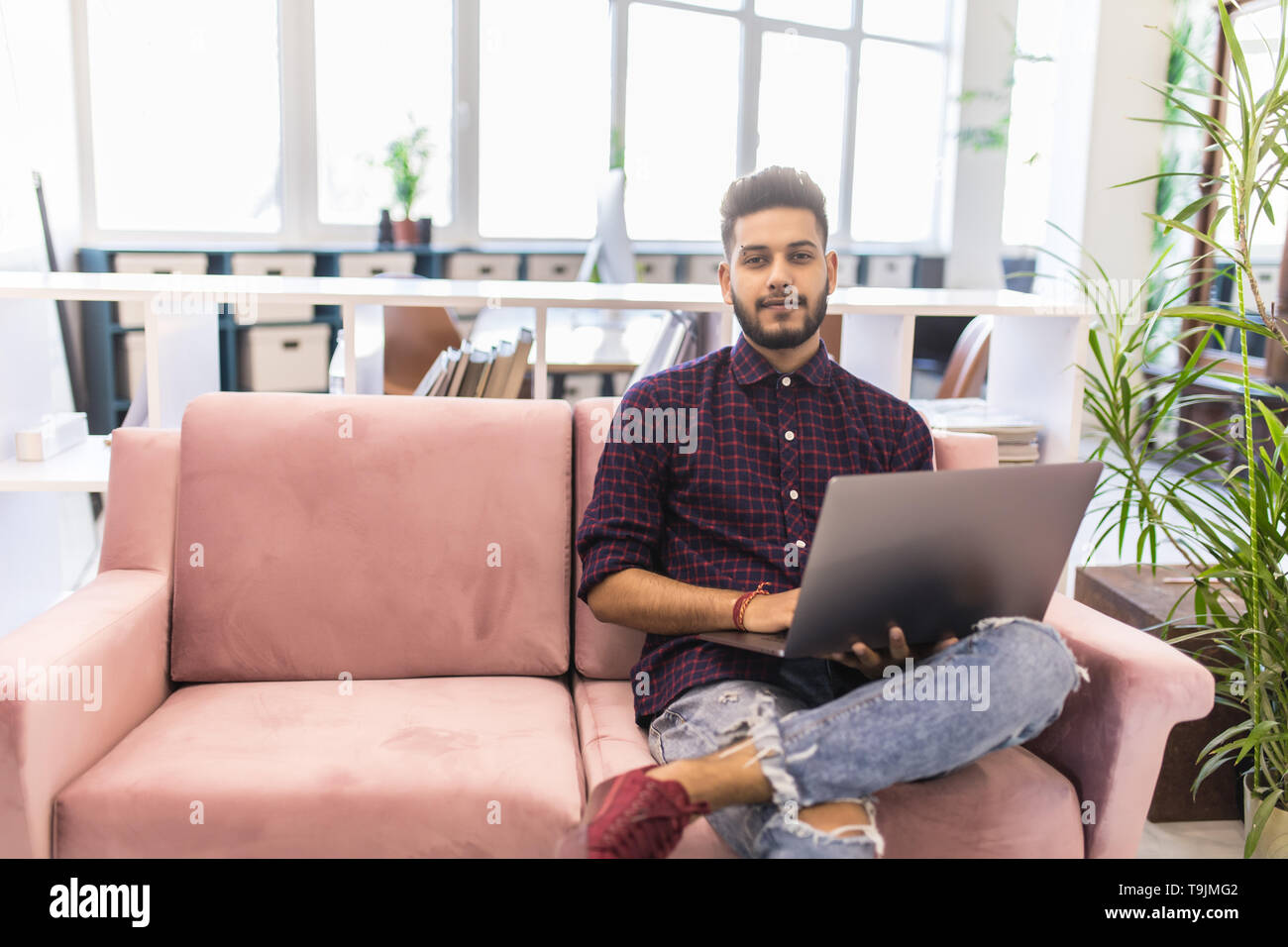 Casual young man using laptop with happy on sofa in modern office ...