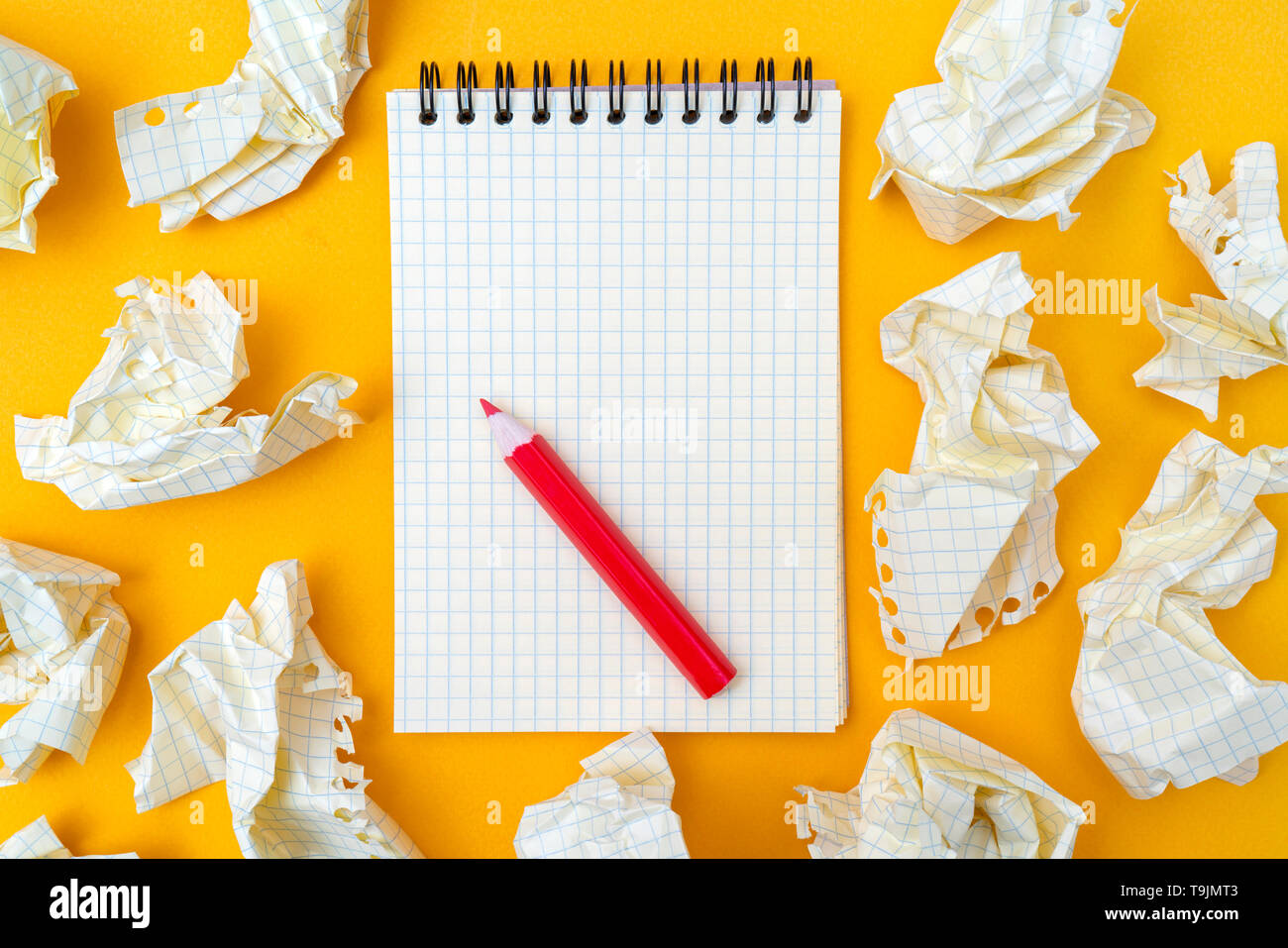 Red pencil and notebook on a yellow background. Crumpled sheets of ...