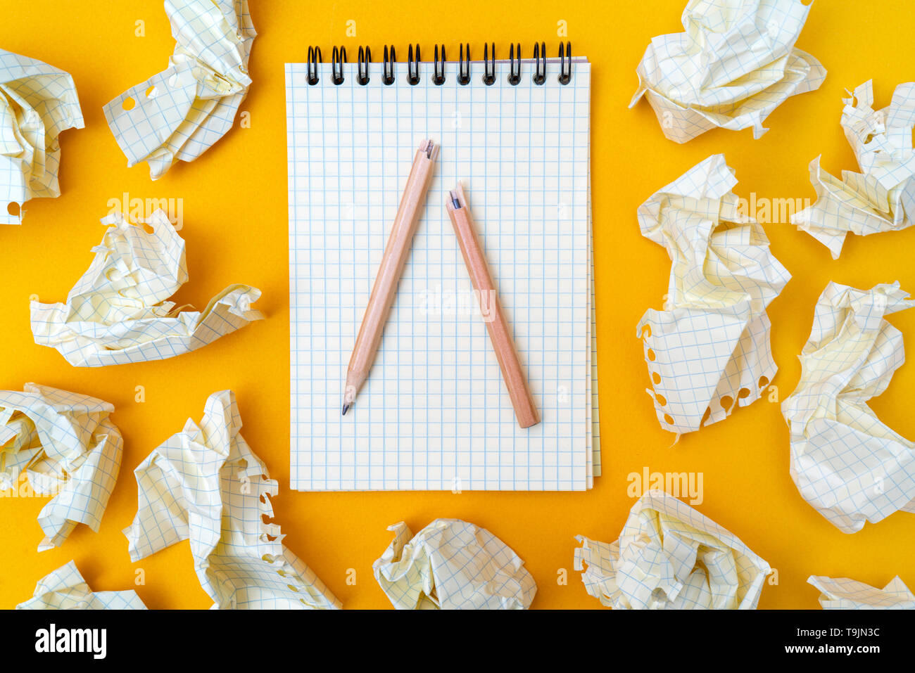 Pencil and notebook on a yellow background. Crumpled sheets of paper ...