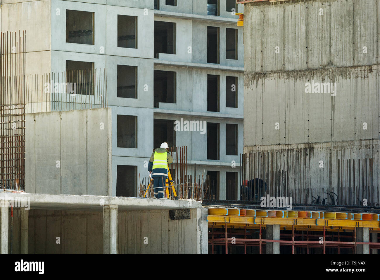 The builder in yellow overalls makes a topographic survey against the ...