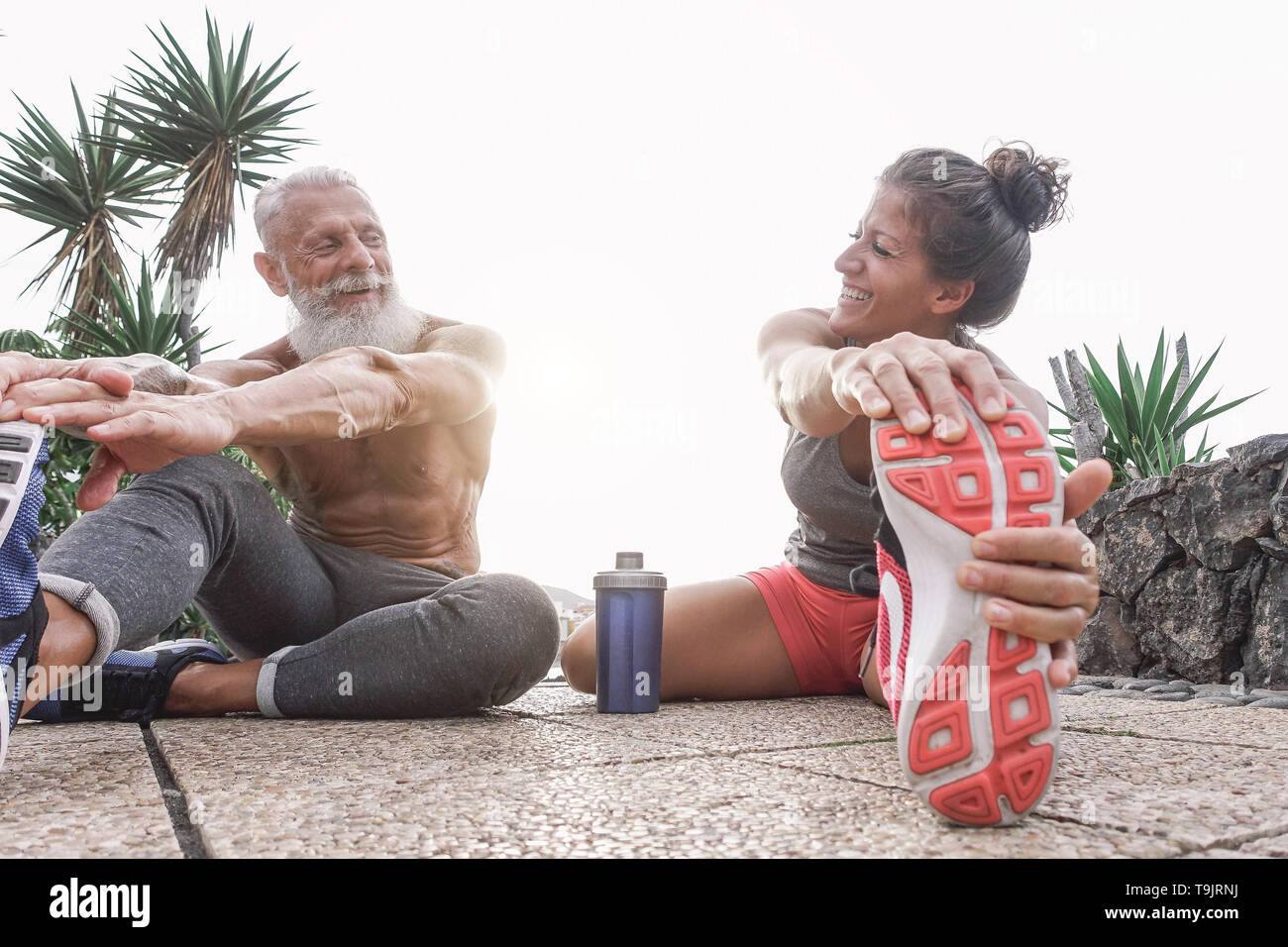 Happy fitness friends doing legs stretching exercises together in ...