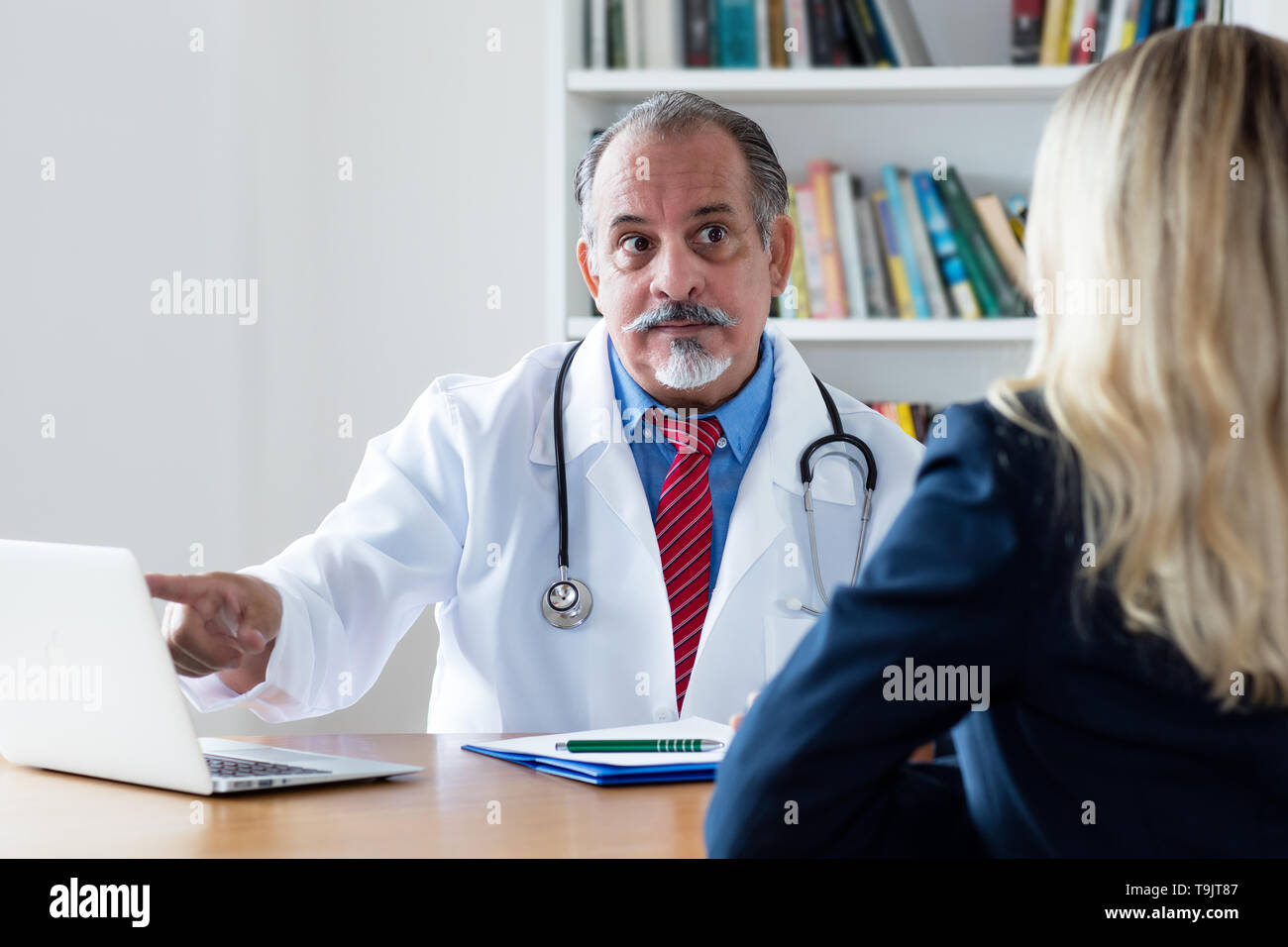 General practitioner explaining diagnosis to female patient at hospital ...
