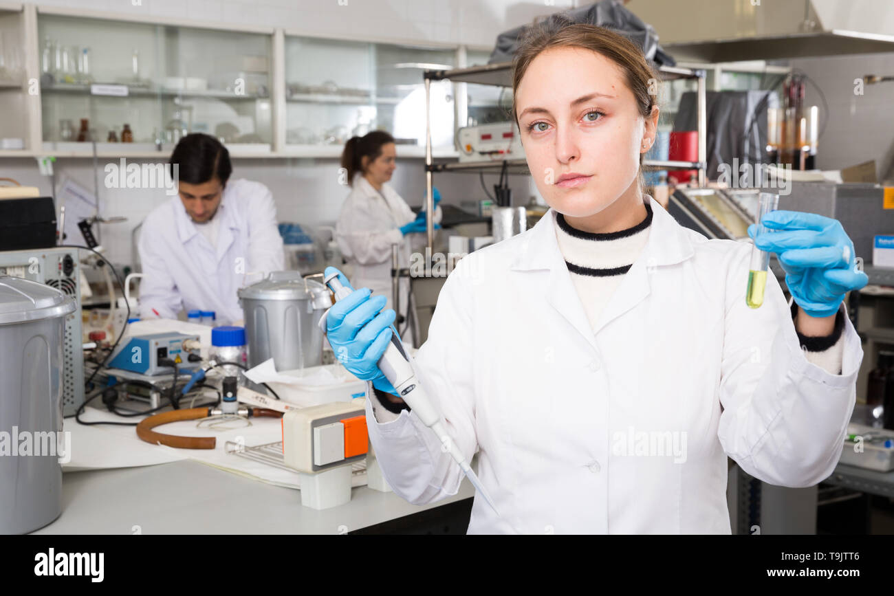 Young female lab technician working with reagents in test tubes during ...