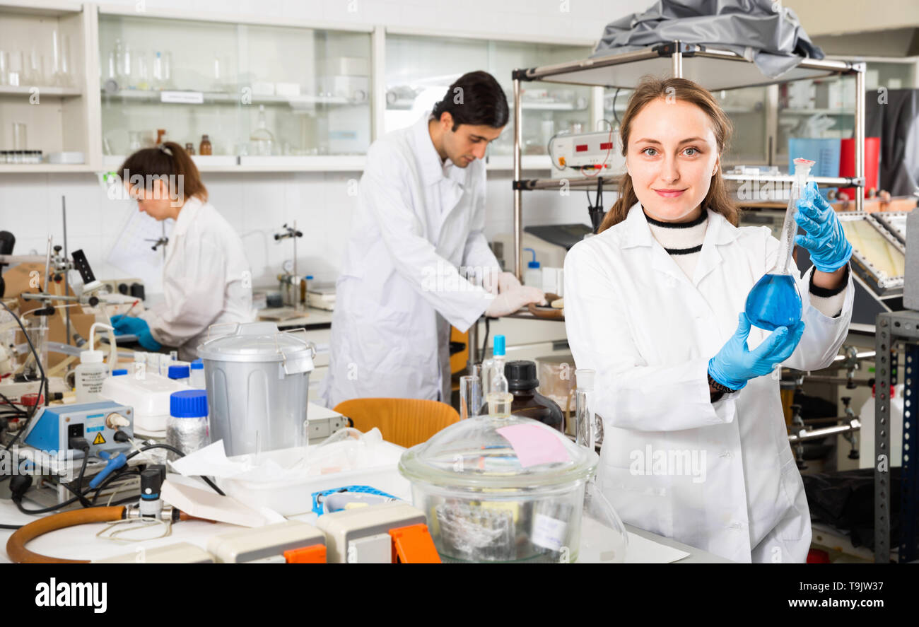 Young positive female lab technician working with reagents in test ...