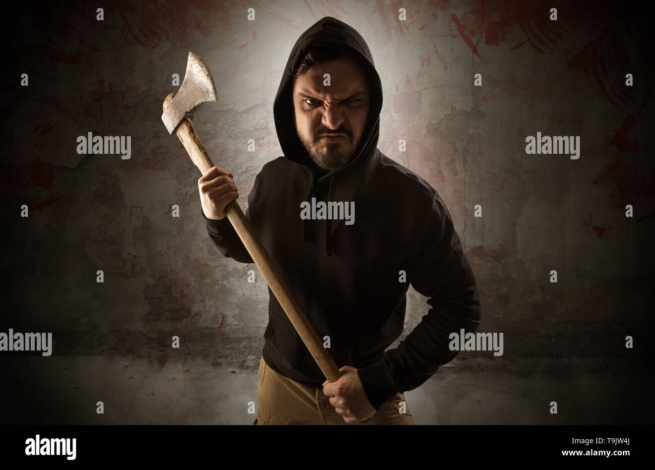 Armed rude assassin in an empty bloody room concept with gun ax ...