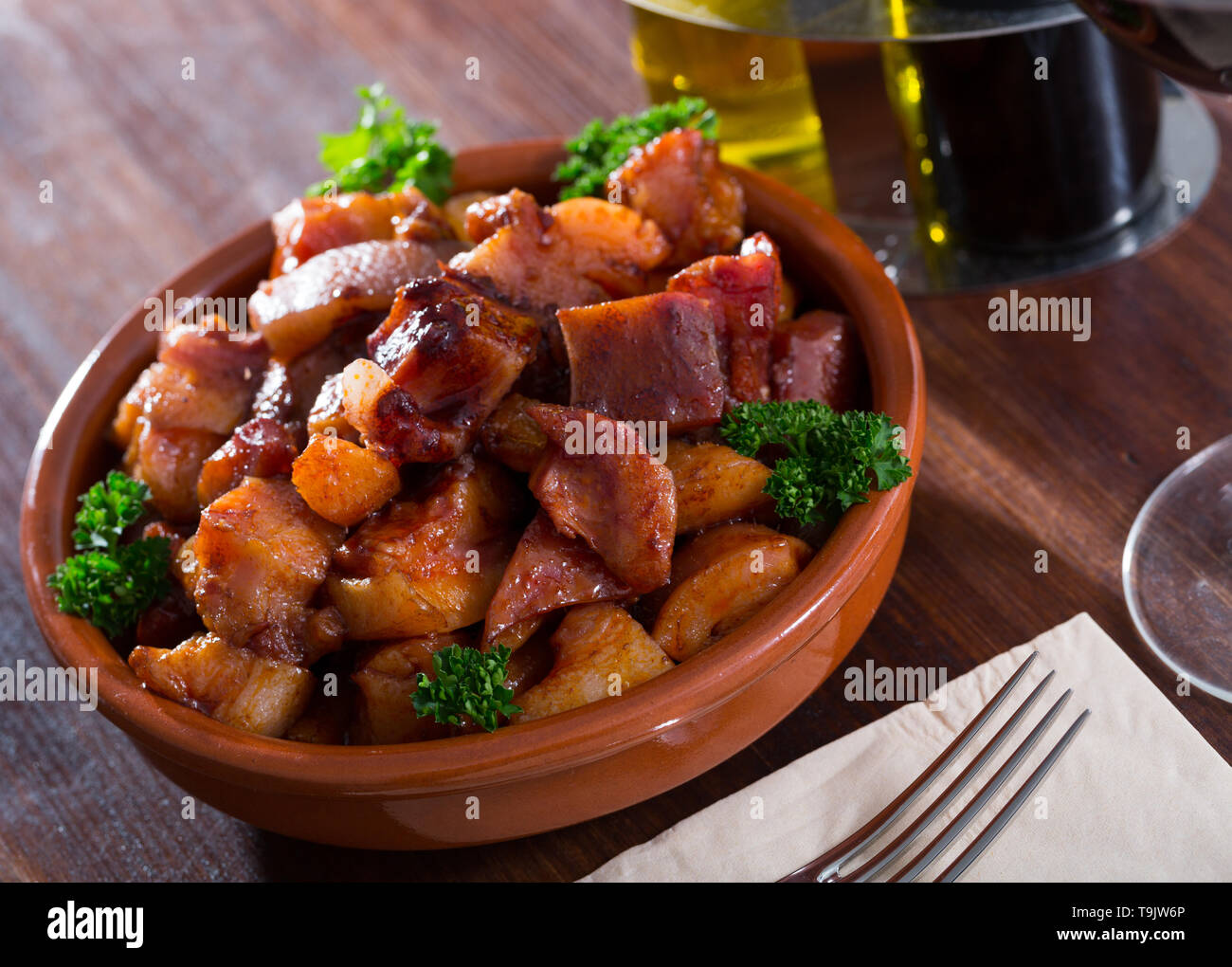 Roasted chopped pig snout served with leaves of parsley on clay bowl ...