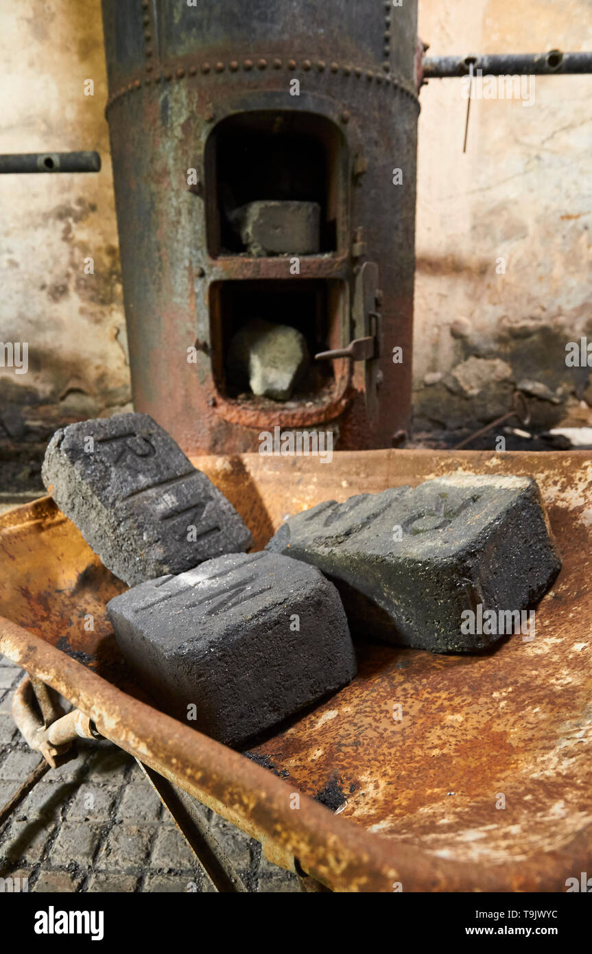 Old coal bricks in rusty wheelbarrow and old metal boilers at the ...