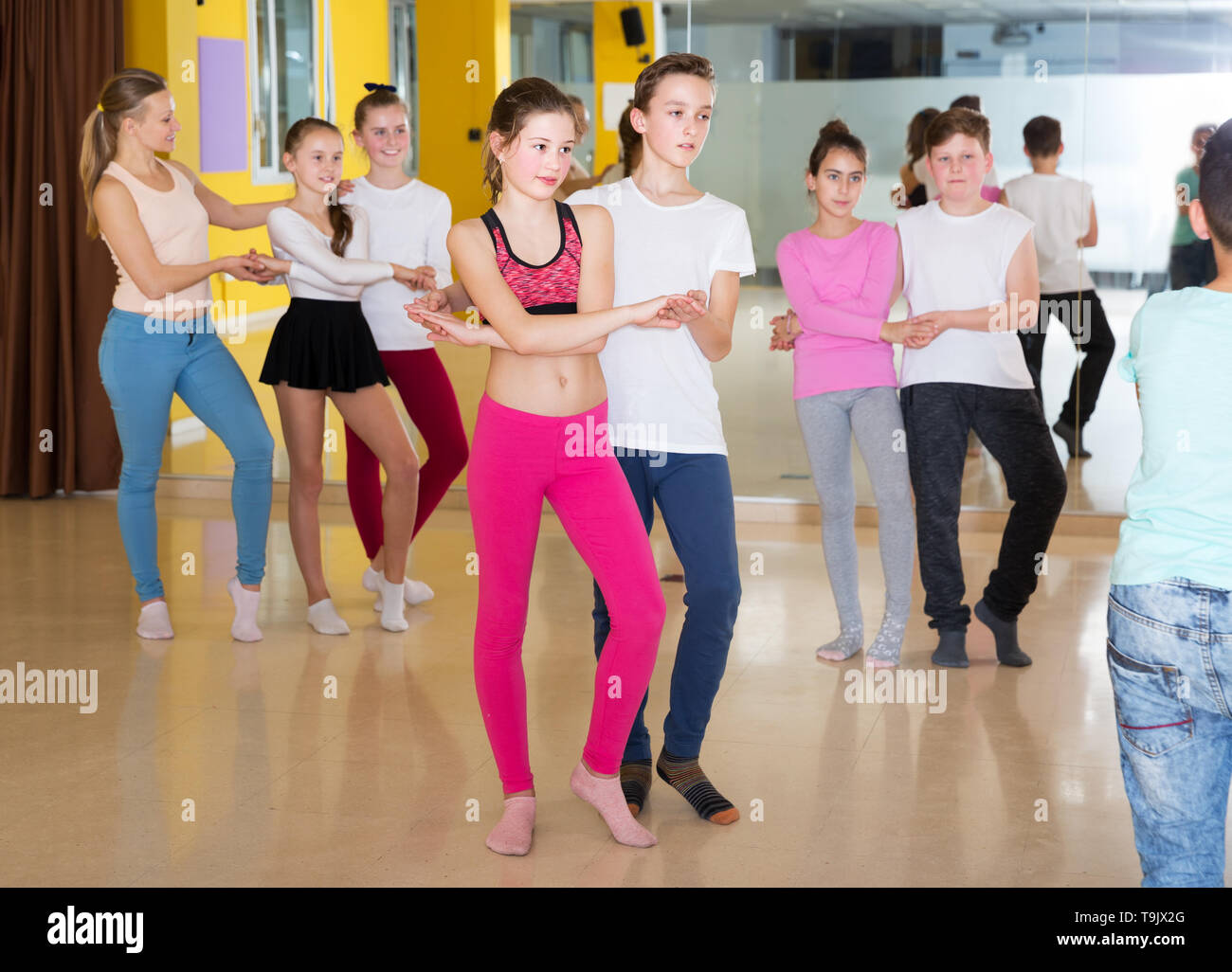 Group of tweens practicing vigorous jive movements in dance studio with ...