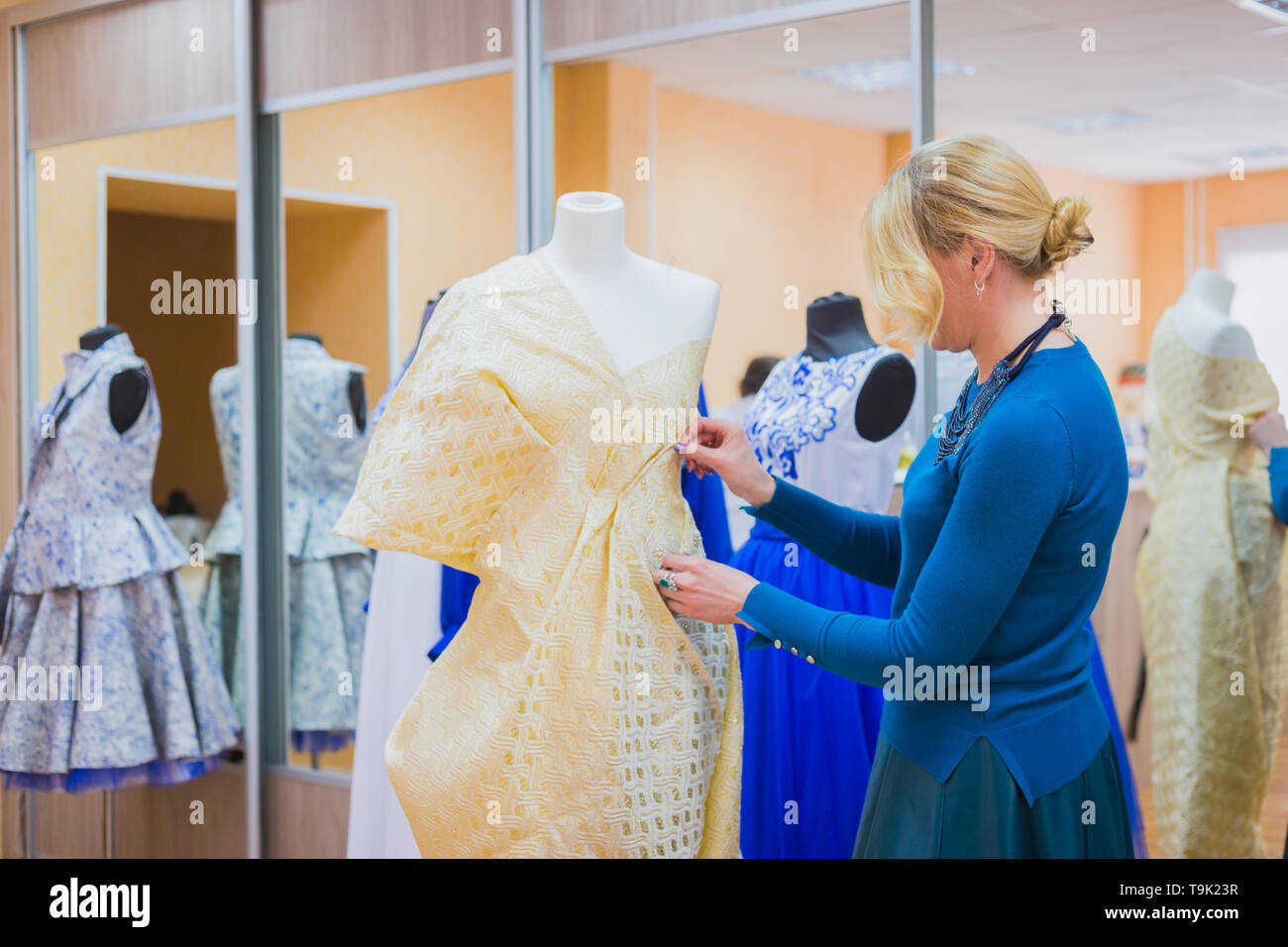 Fashion designer working with new model tailoring dress on mannequin ...