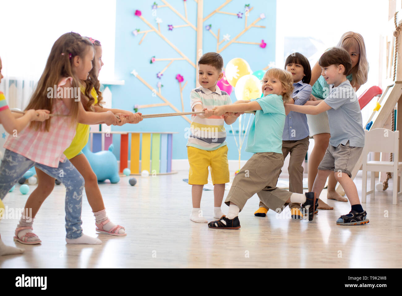 group of preschool kids play and pull rope together in daycare Stock ...