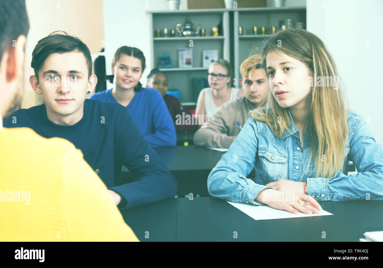 Group of students listening attentively to teacher explaining material ...