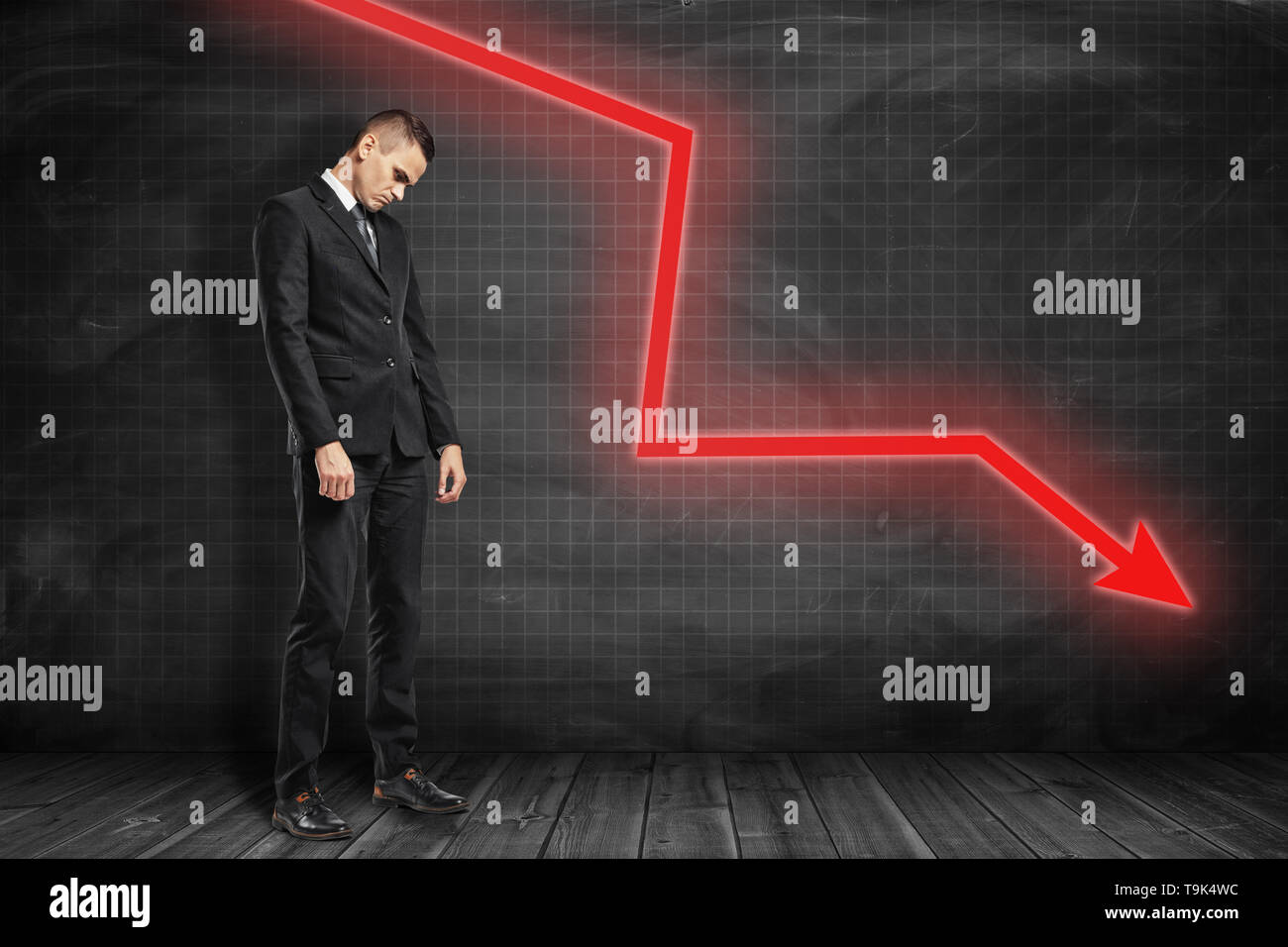 Sad businessman with red arrow going down on black background Stock ...