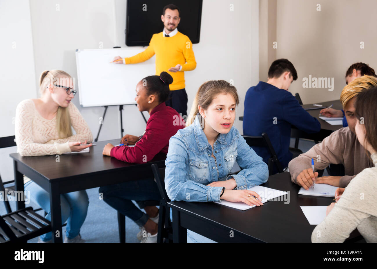 Smiling classmates working in groups to complete task during class ...