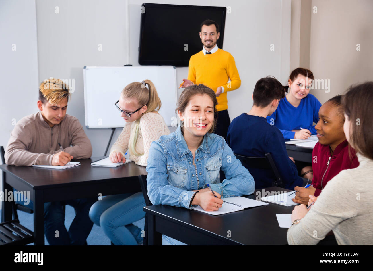 Smiling positive fellow students having group work tasks during school ...