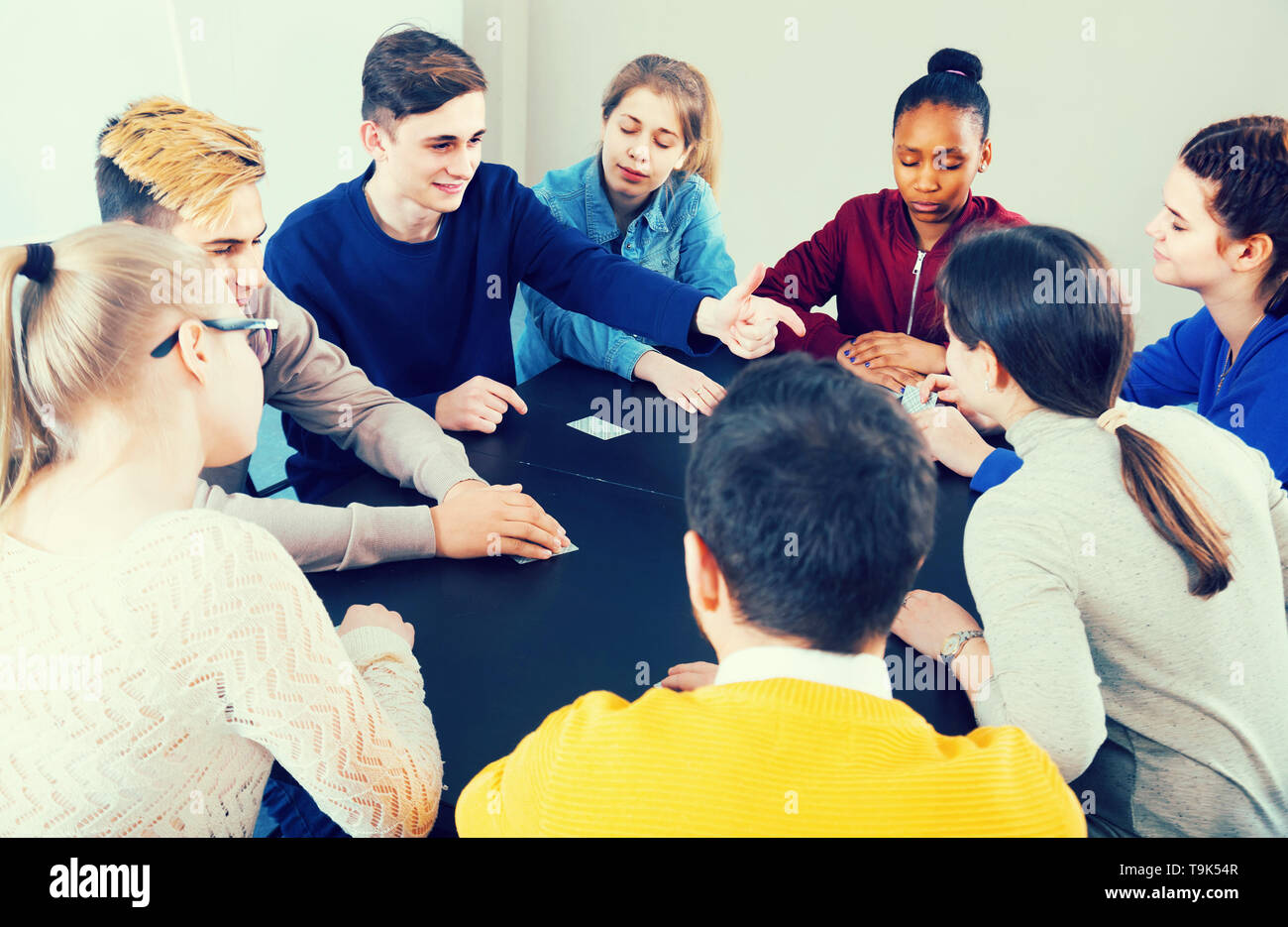 positive american classmates having round of Werewolf game at break ...