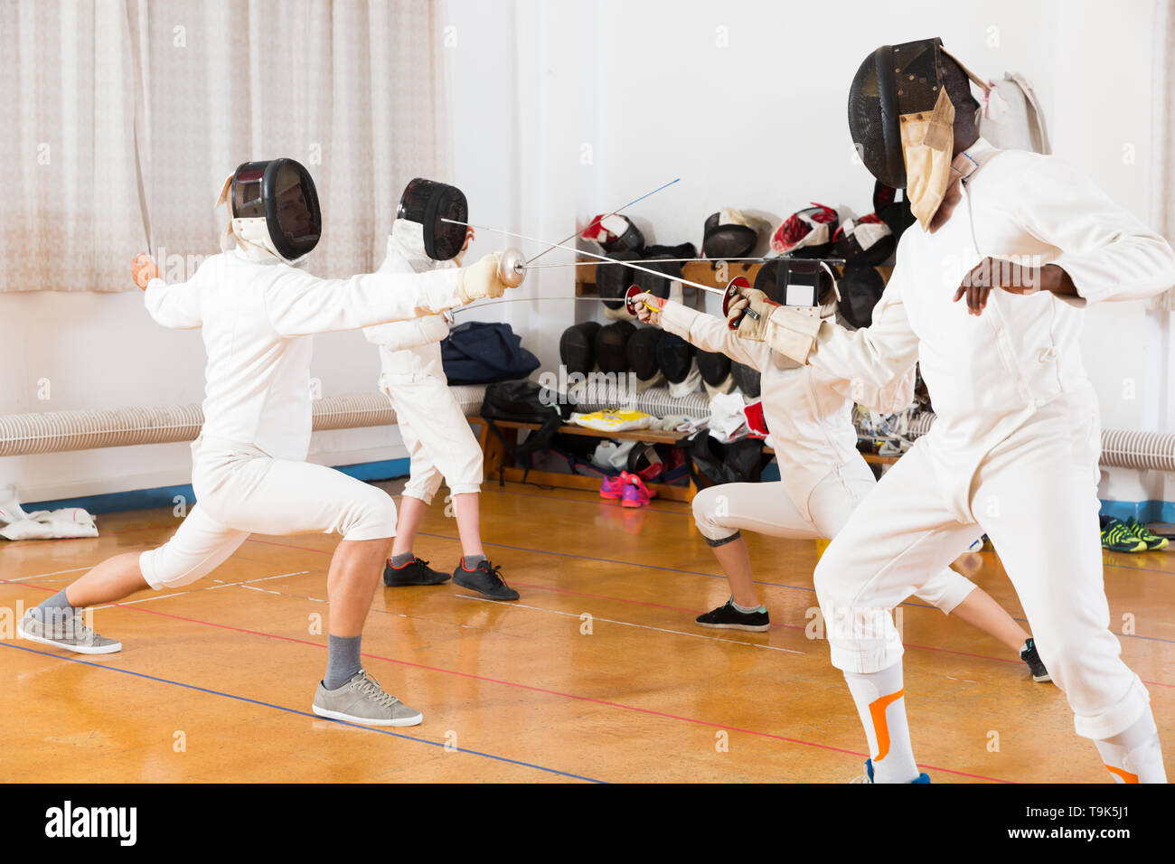 Cheerful group practicing effective fencing techniques in sparring in ...