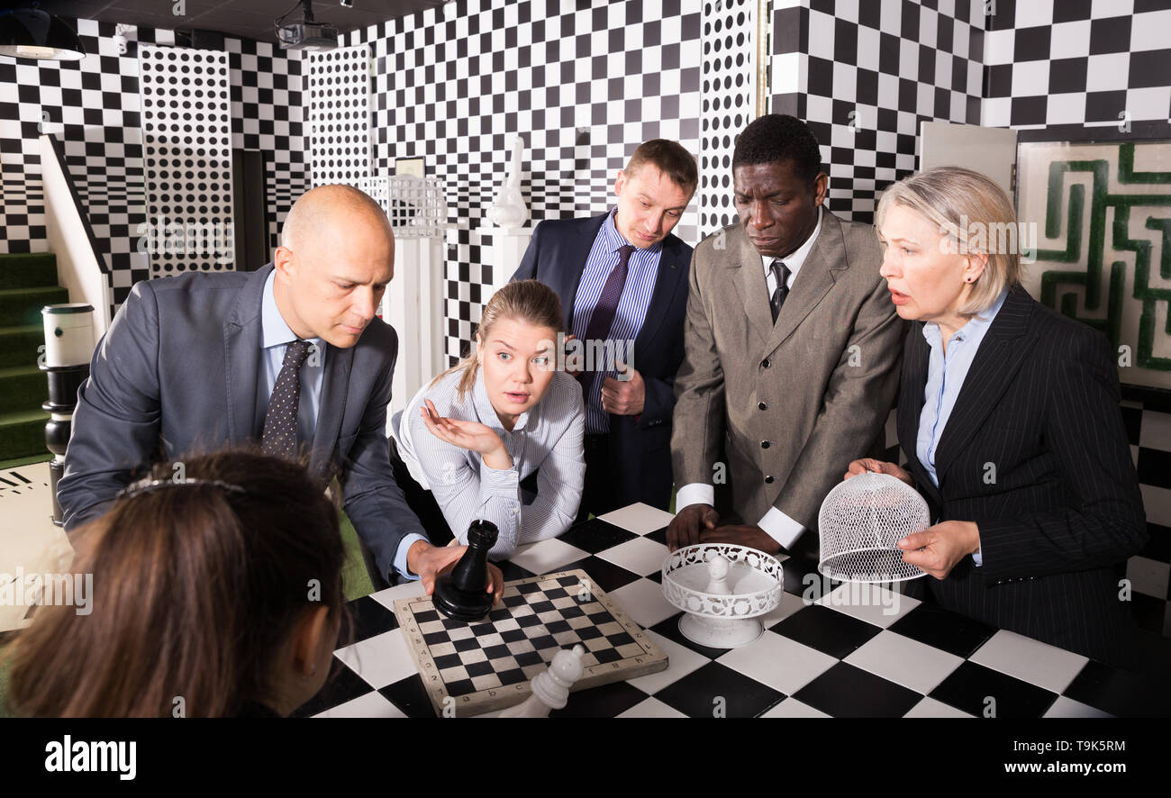 Men and women in business suits solving puzzles with chess to get out ...