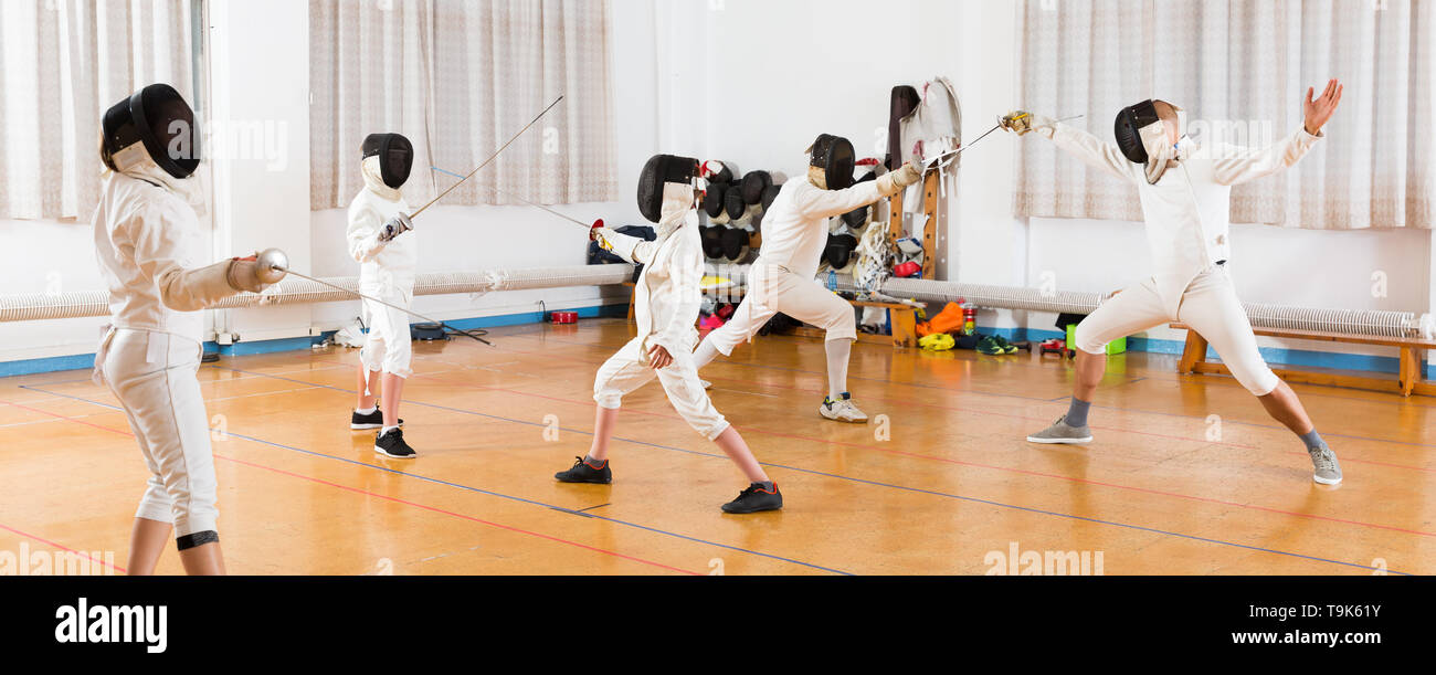 Adults and teens wearing fencing uniform practicing with foil at the ...