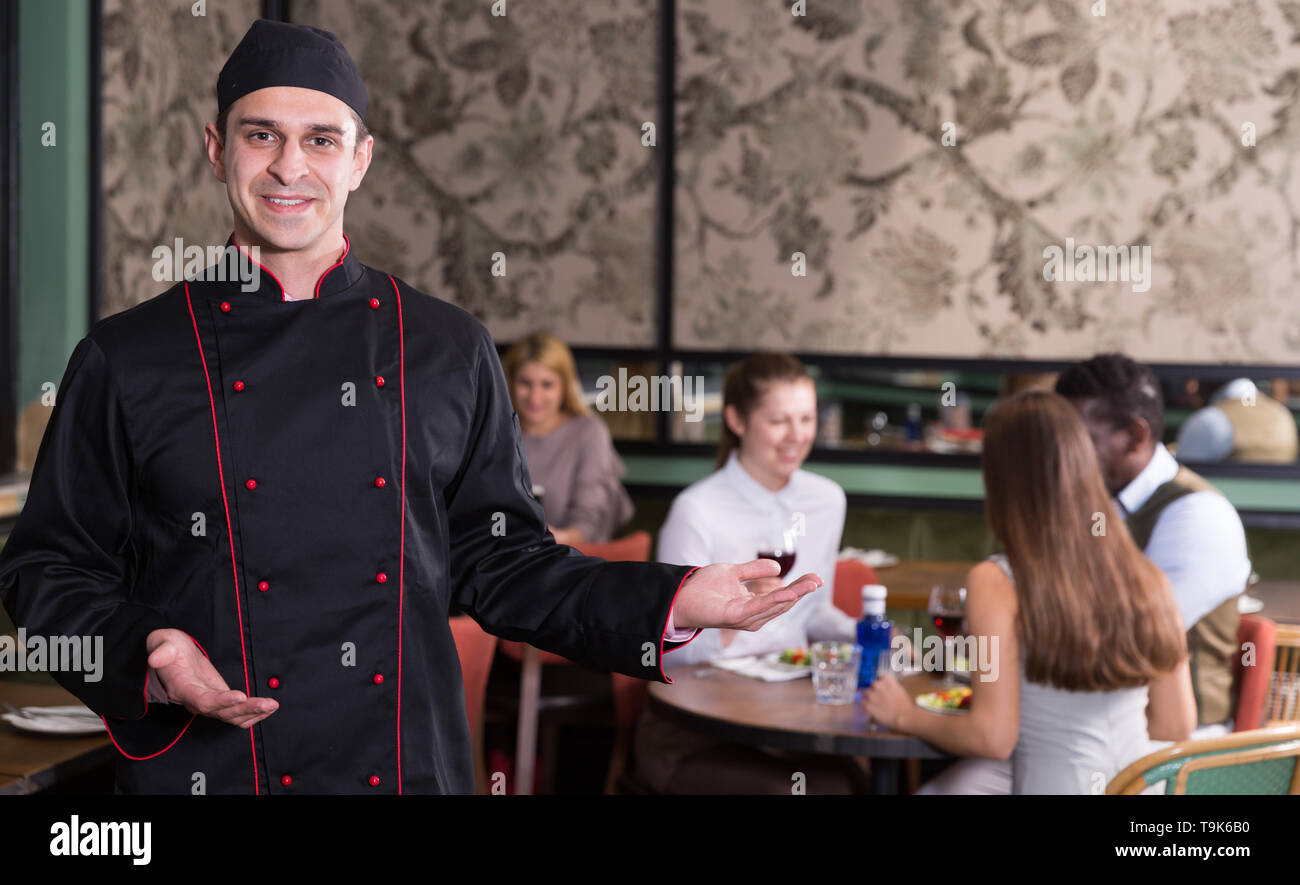 Portrait of confident smiling chef standing in restaurant hall with ...