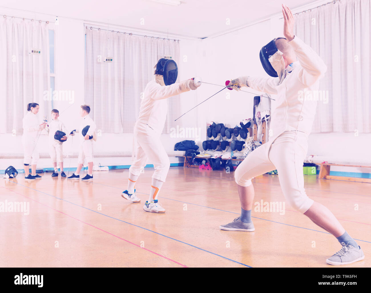 Serious group practicing effective fencing techniques in sparring in ...