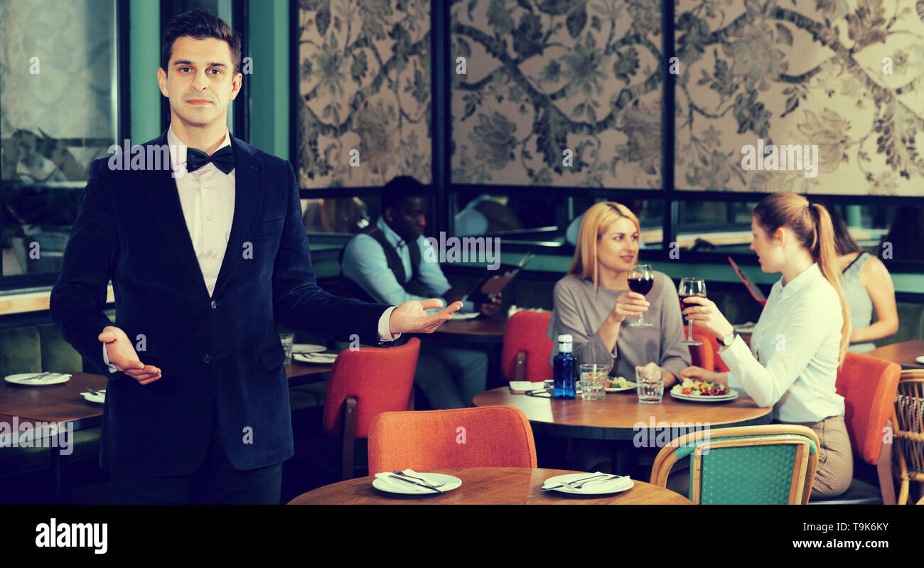 Handsome elegant waiter standing with welcome gesture in restaurant ...