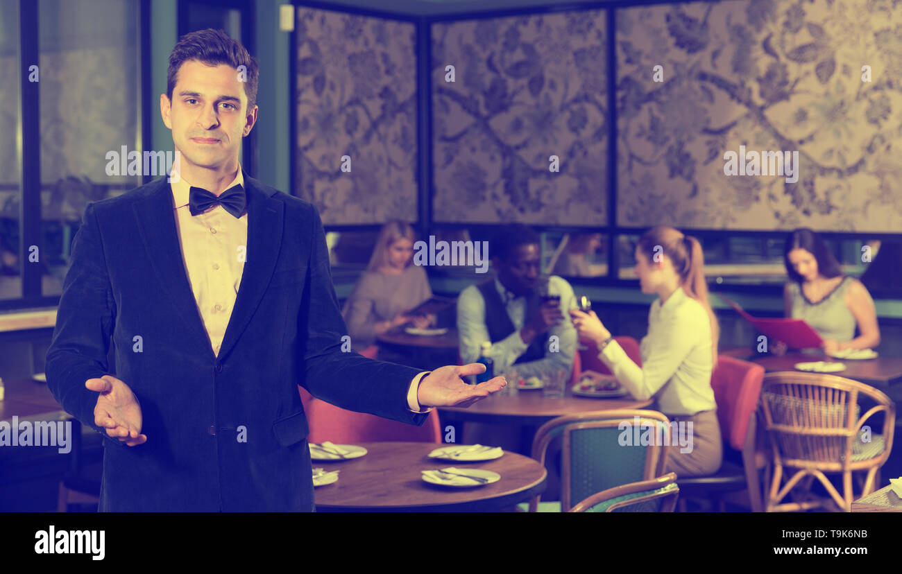 Handsome elegant waiter standing with welcome gesture in restaurant ...