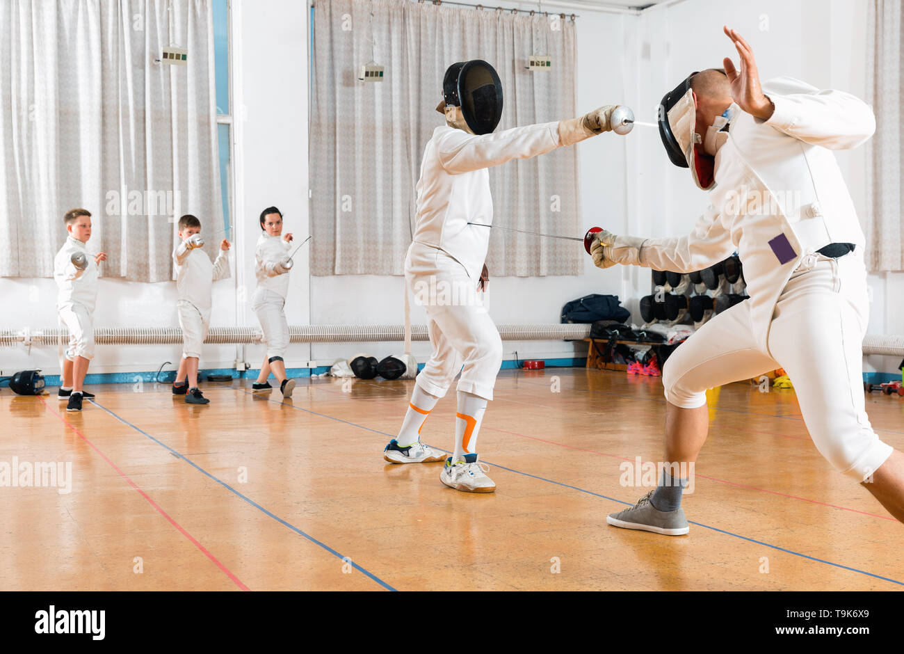 Positive coaches demonstrating to young athletes attack movements with ...