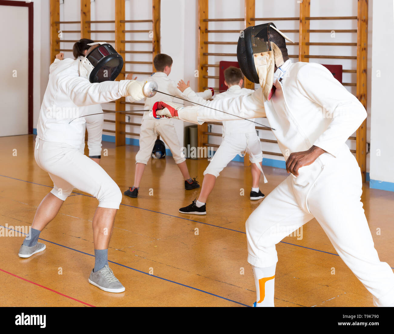 Joyful group practicing effective fencing techniques in sparring in ...
