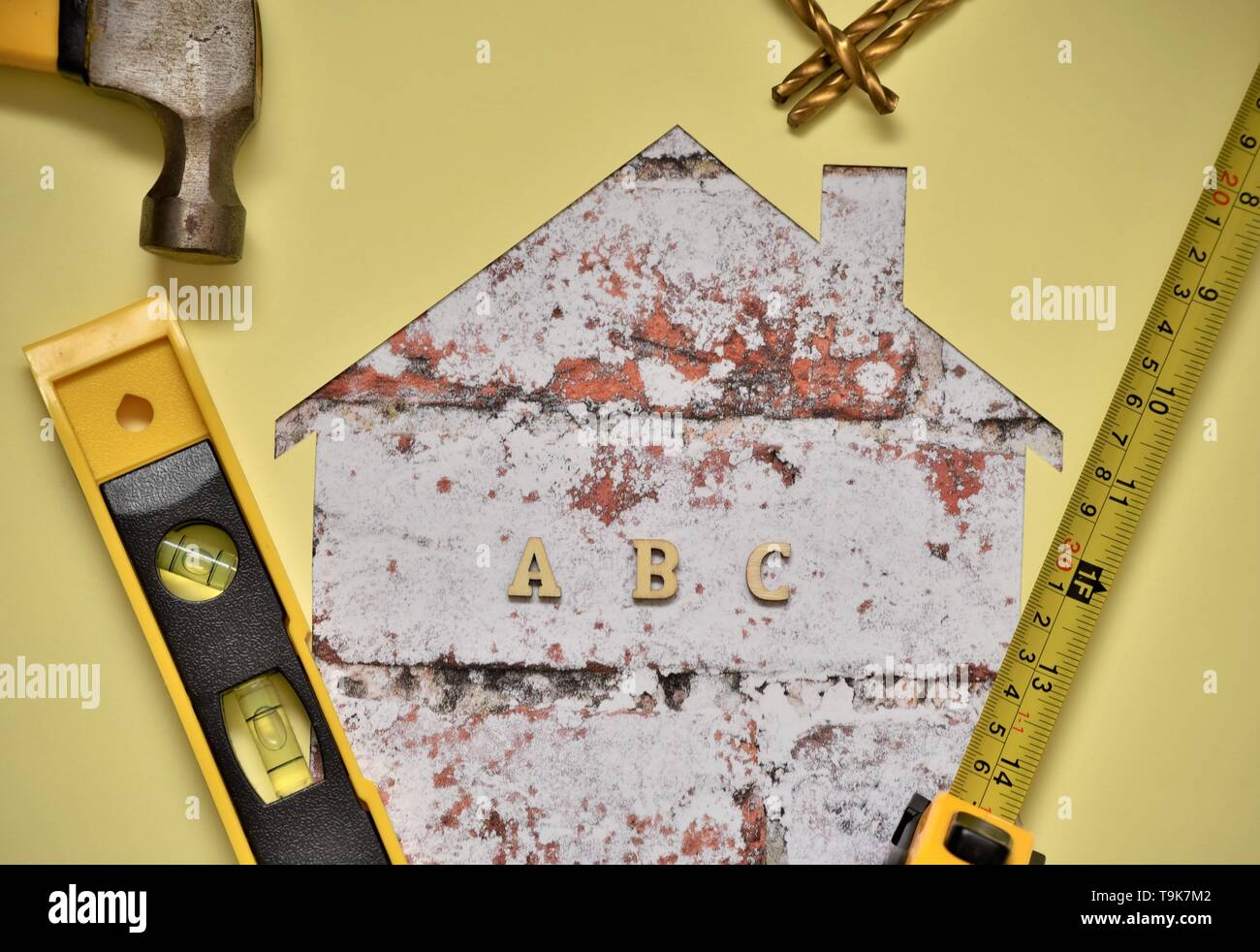 House shaped paper cut out filled with brick background with tools and ...