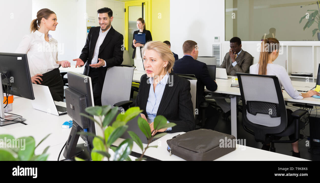 Successful coworkers engaged in business activities in busy open plan ...
