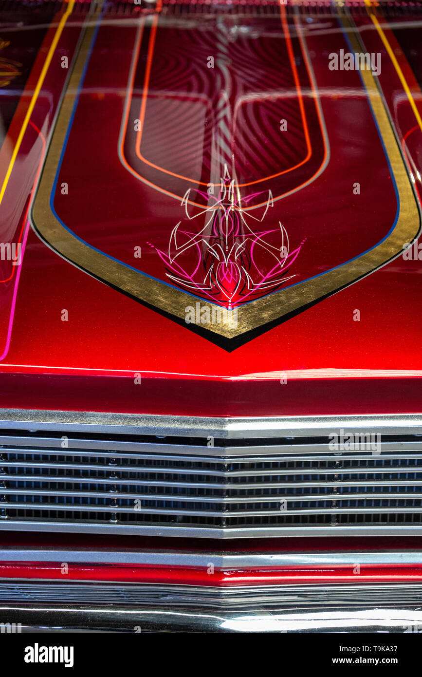 Detail of the hood of a red and chrome car with hand-painted lines ...