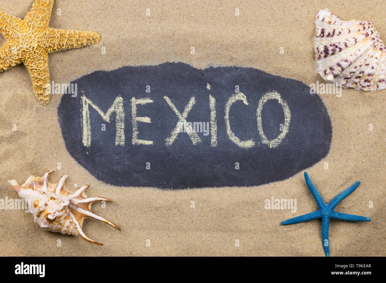 Handwritten word MEXICO written in chalk, among seashells and ...