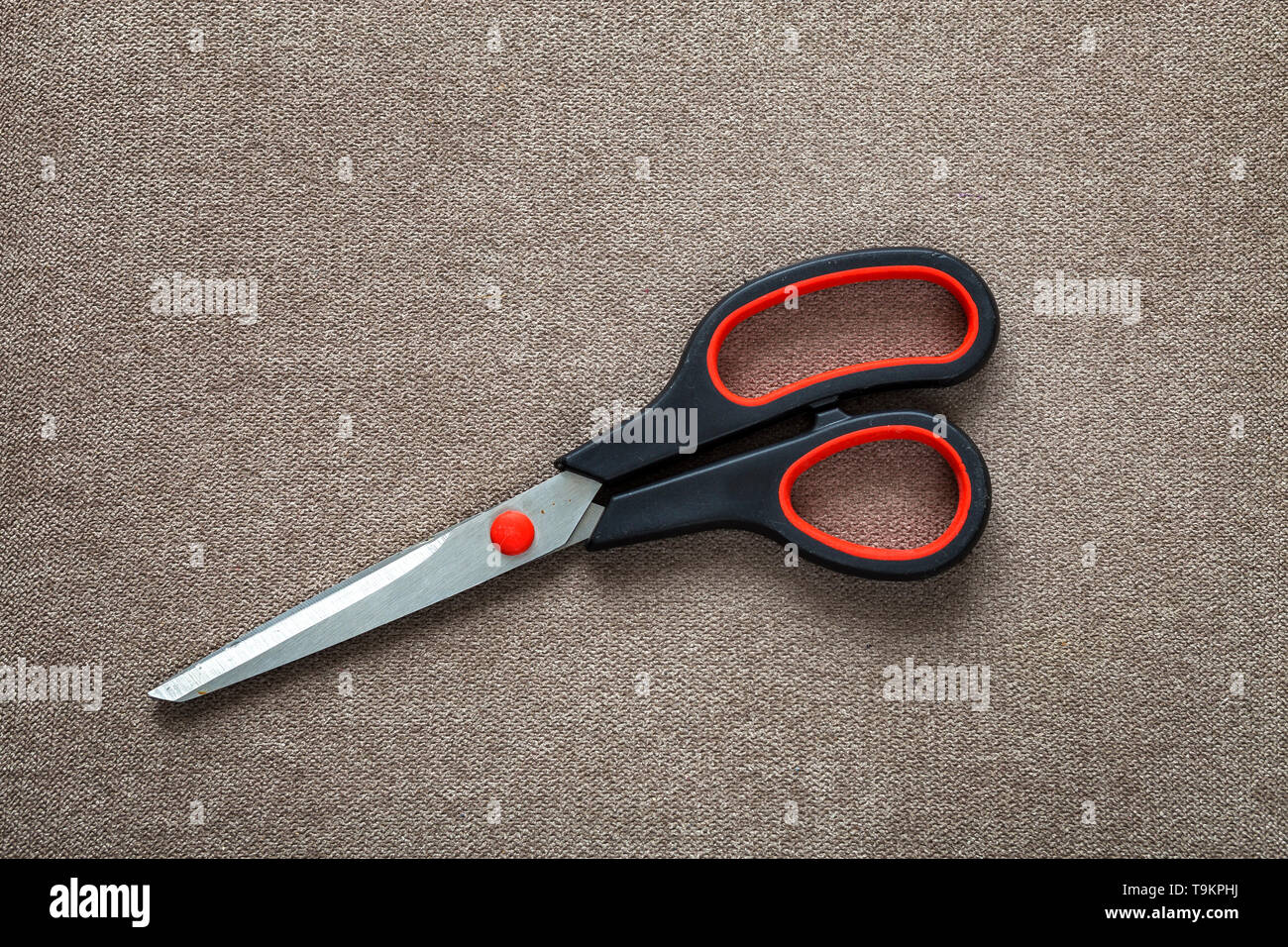 Close-up of sharp steel metal scissors isolated on light cloth copy ...