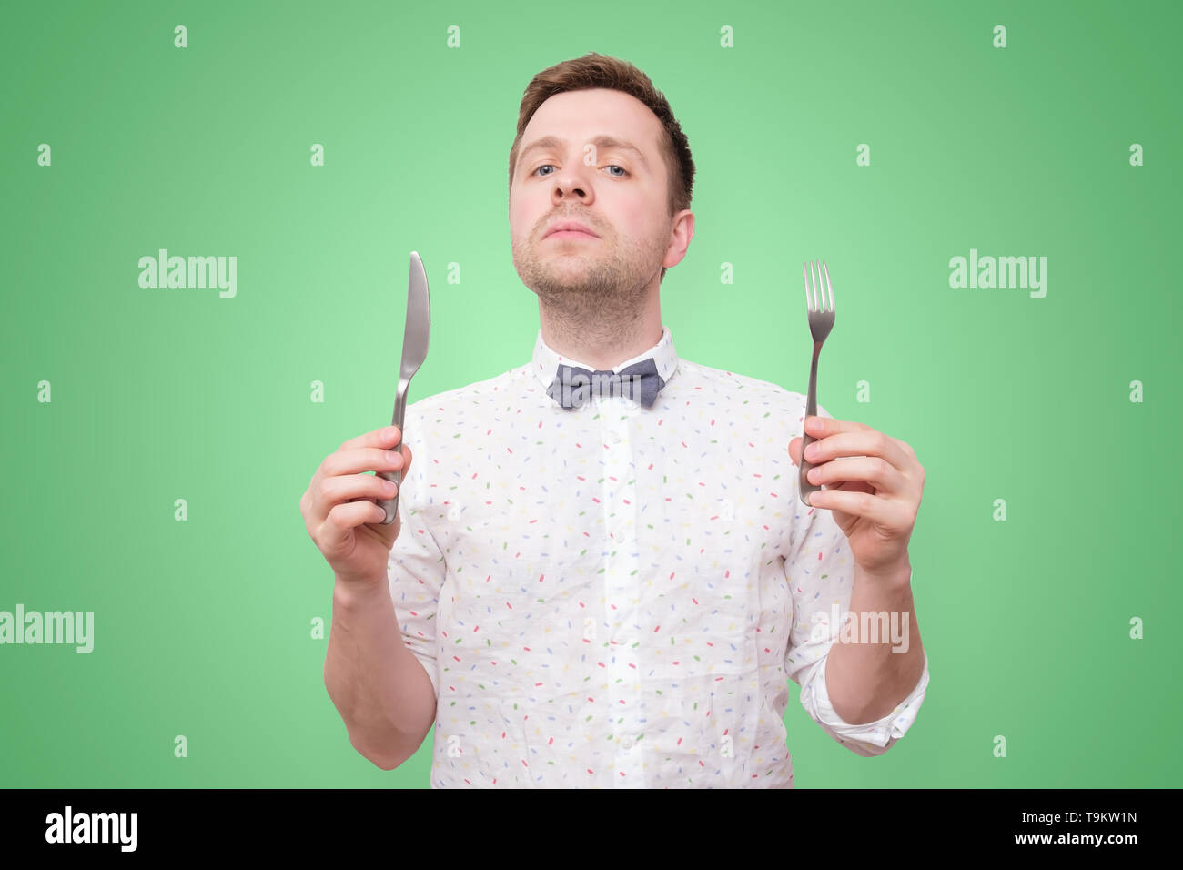 Hungry man holding fork and knife on hand to eat Stock Photo - Alamy